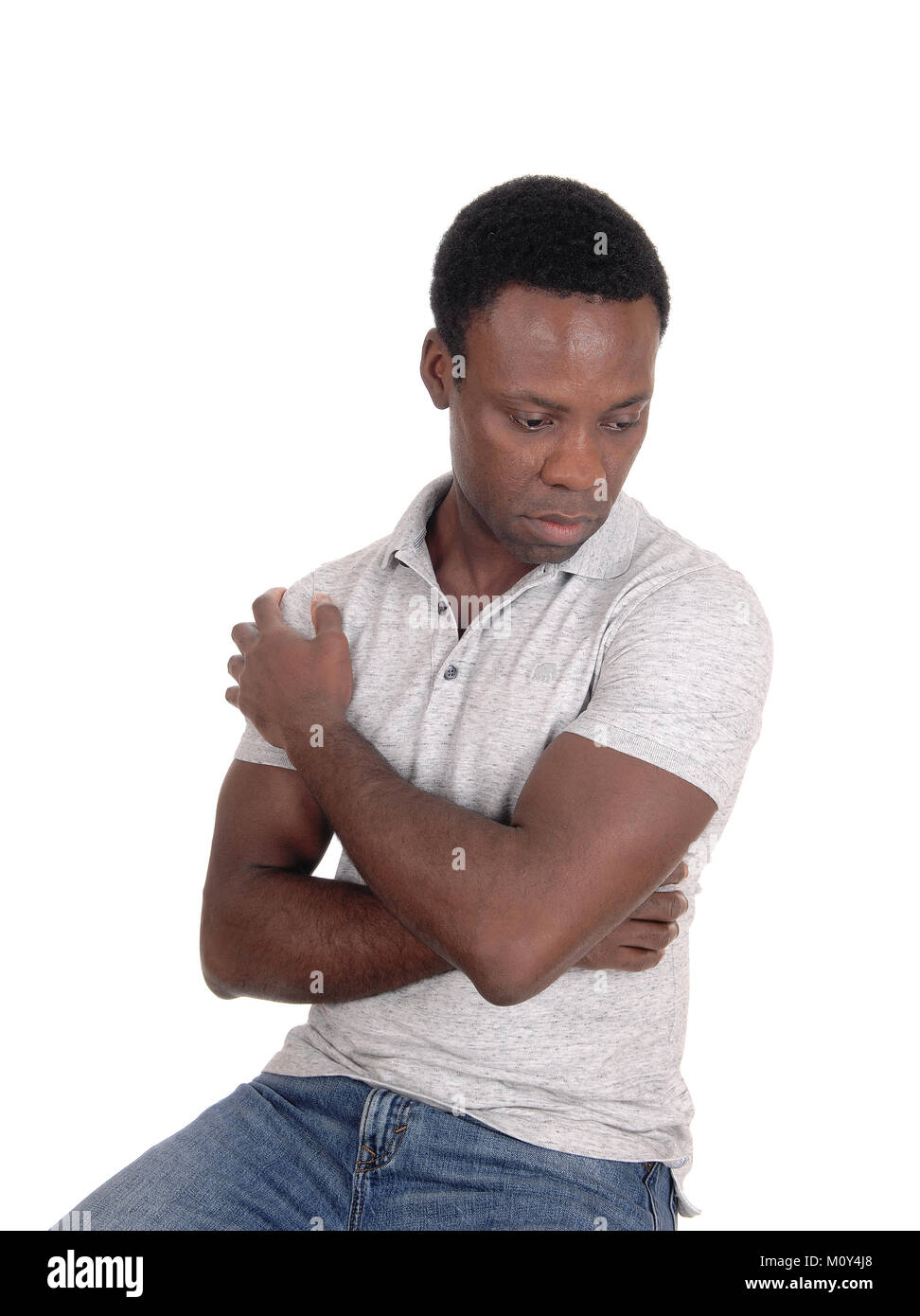 A young African American man sitting and looking down very sad and ...