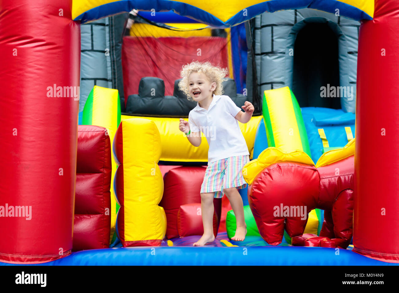 Child jumping on colorful playground trampoline. Kids jump in ...