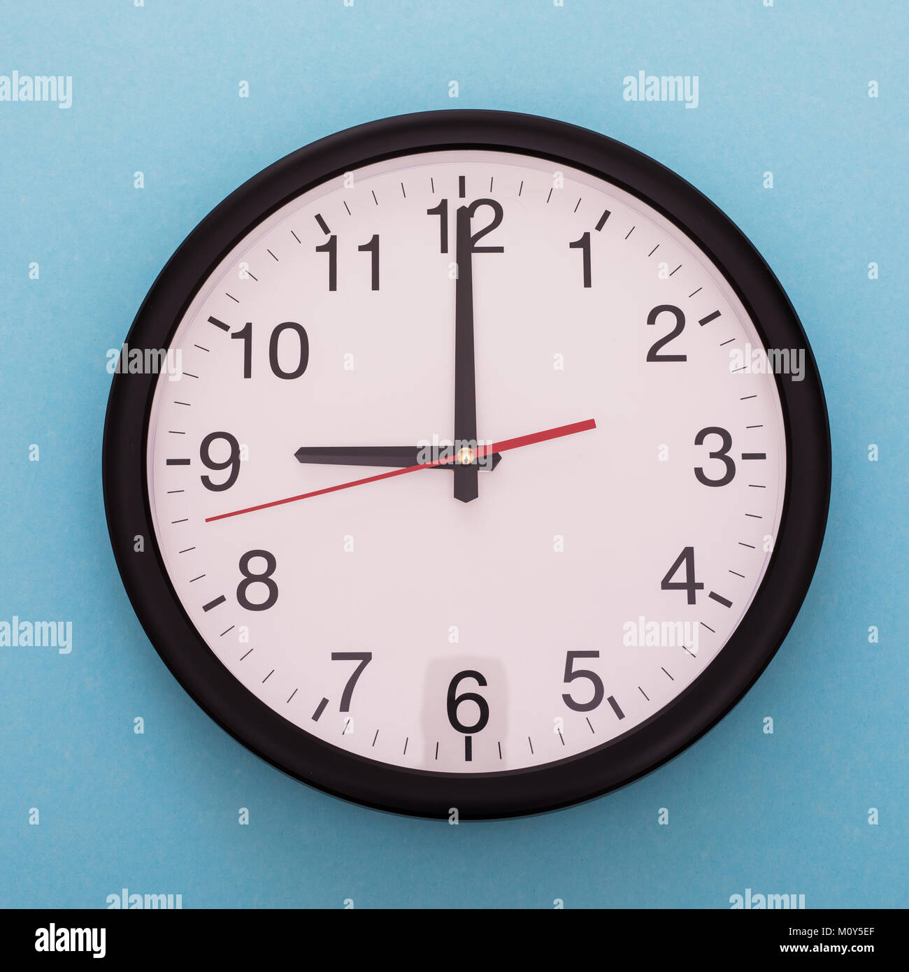 Big wall clock isolated on blue background Stock Photo - Alamy