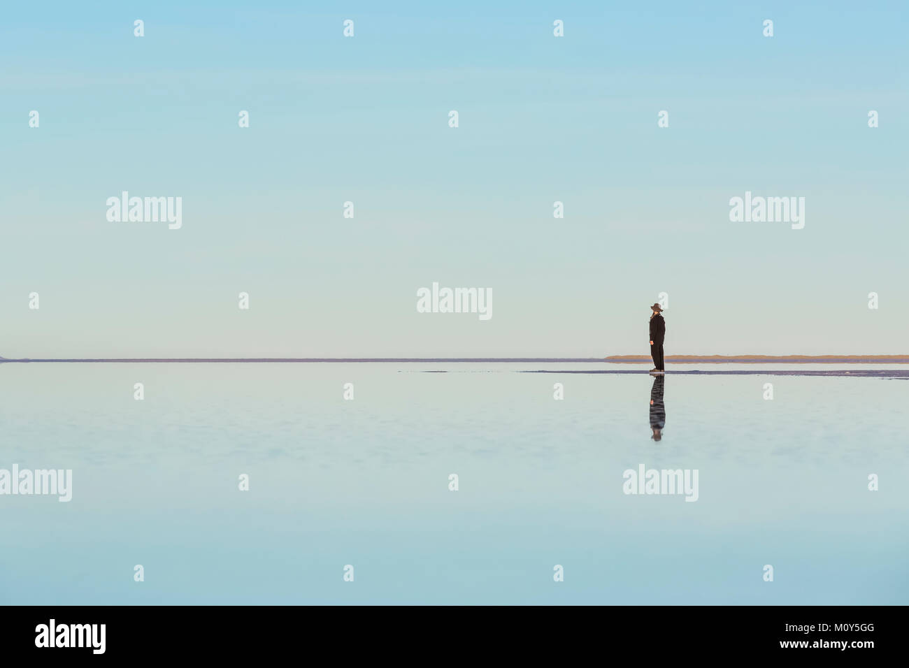 Woman walking on a spit of land extending out into shallow salt water ...