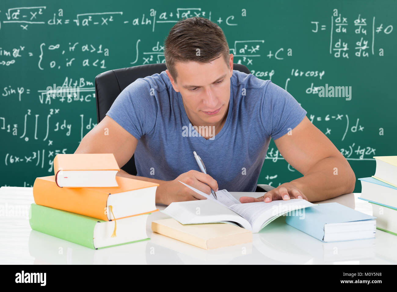 Happy Handsome Young Male University Student Studying In Front Of A ... Happy Handsome Young Male University Student Studying In Front Of A ...