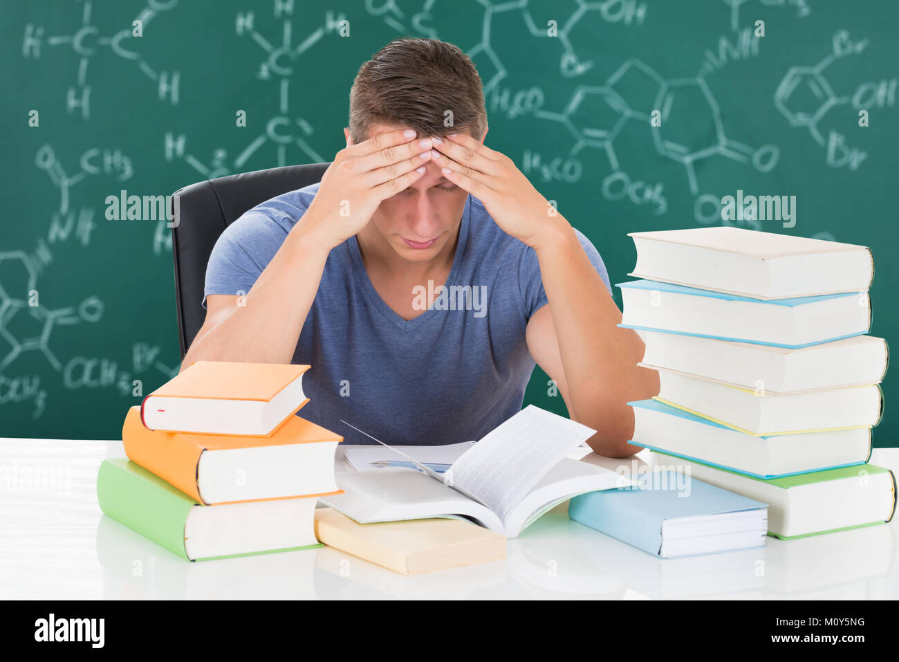 Young Worried University Student With Stack Of Books Sitting In Front ...