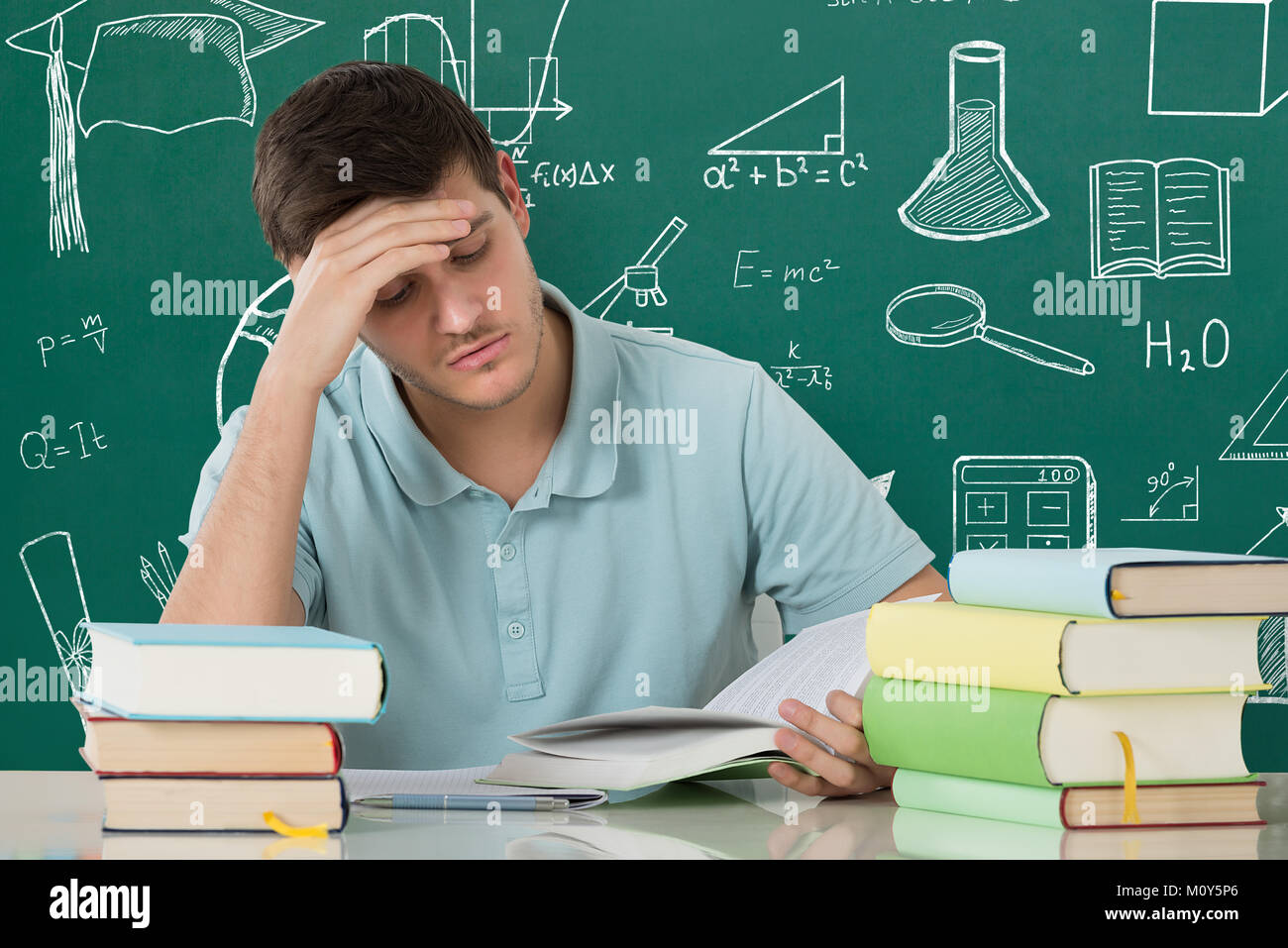 Young Worried University Student With Stack Of Books Sitting In Front ...