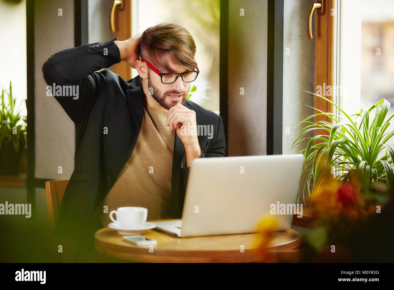 Thoughtful man scratching head at laptop Stock Photo - Alamy