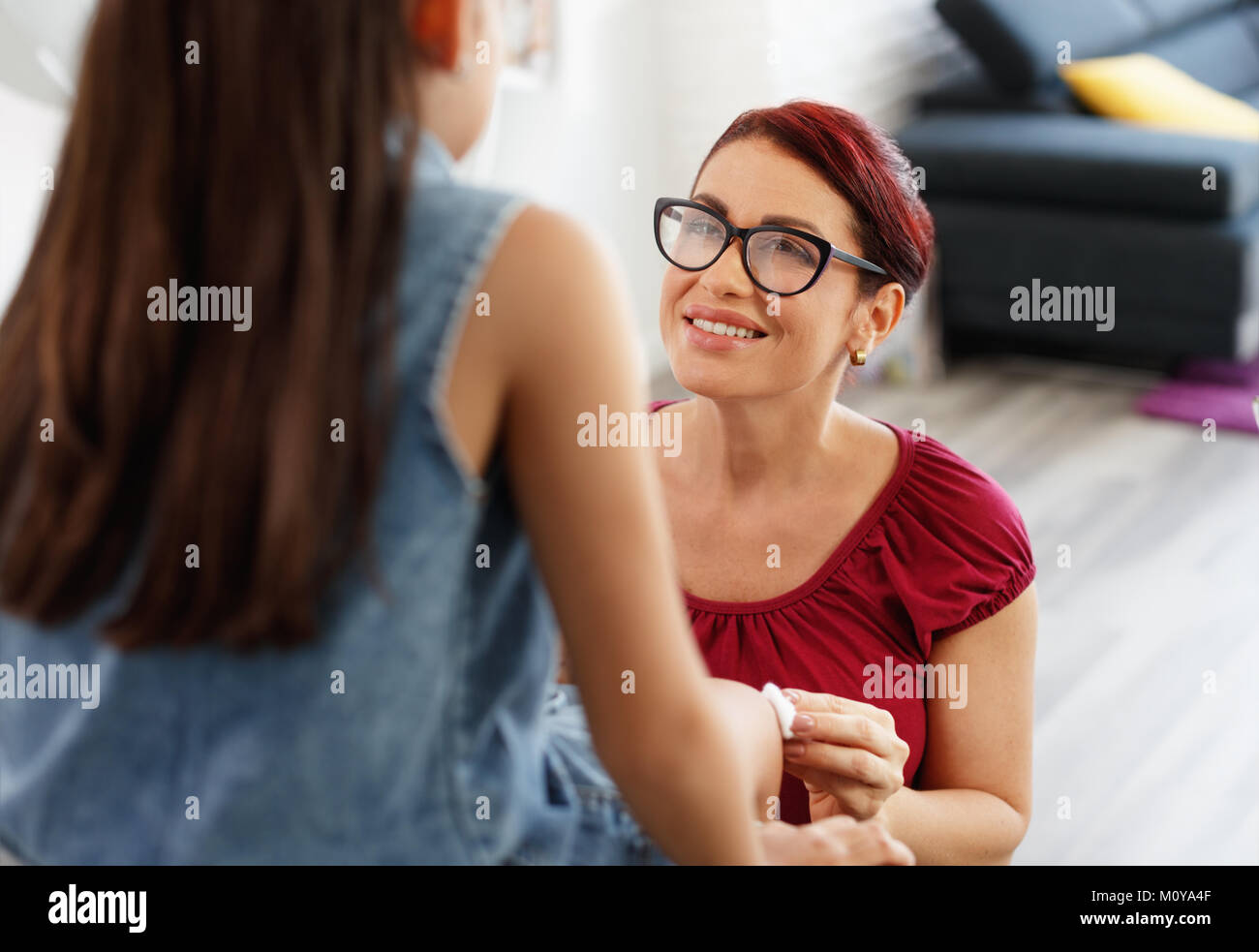 Woman Treating Scratch On Her Daughter Leg At Home Stock Photo - Alamy