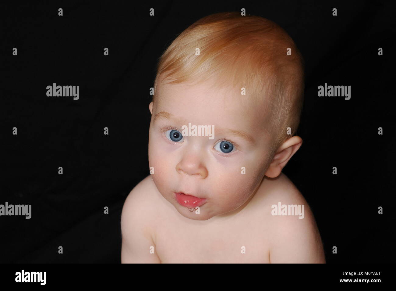 Nine month old baby boy low-key portrait with black back drop. Looking ...