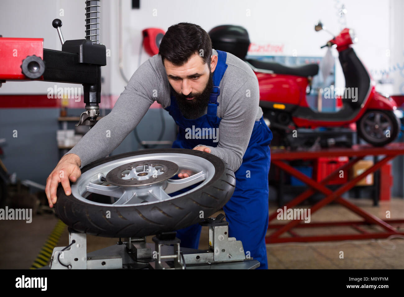 Smiling male worker fixing failed wheel in motorcycle workshop Stock ...