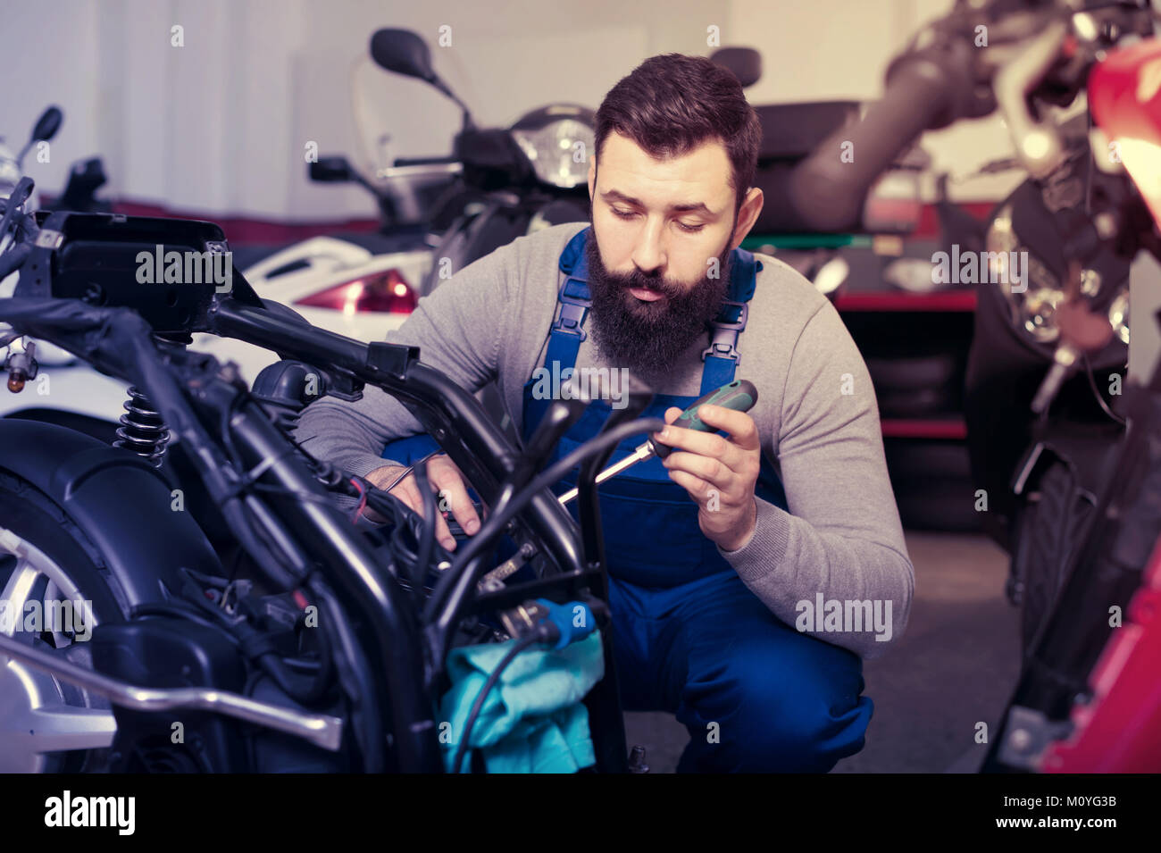 bearded man worker working at restoring motorbike in motorcycle ...