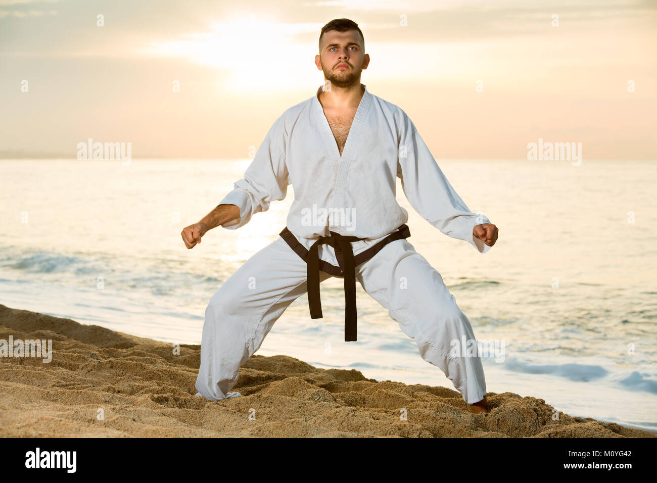 Young sportsman is training the Shiko-dachi stance on the beach near ...