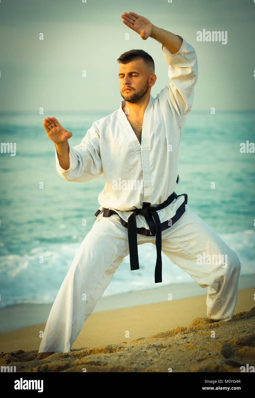 Man is exercising to doing the Shiko-dachi stance on the beach near the ...