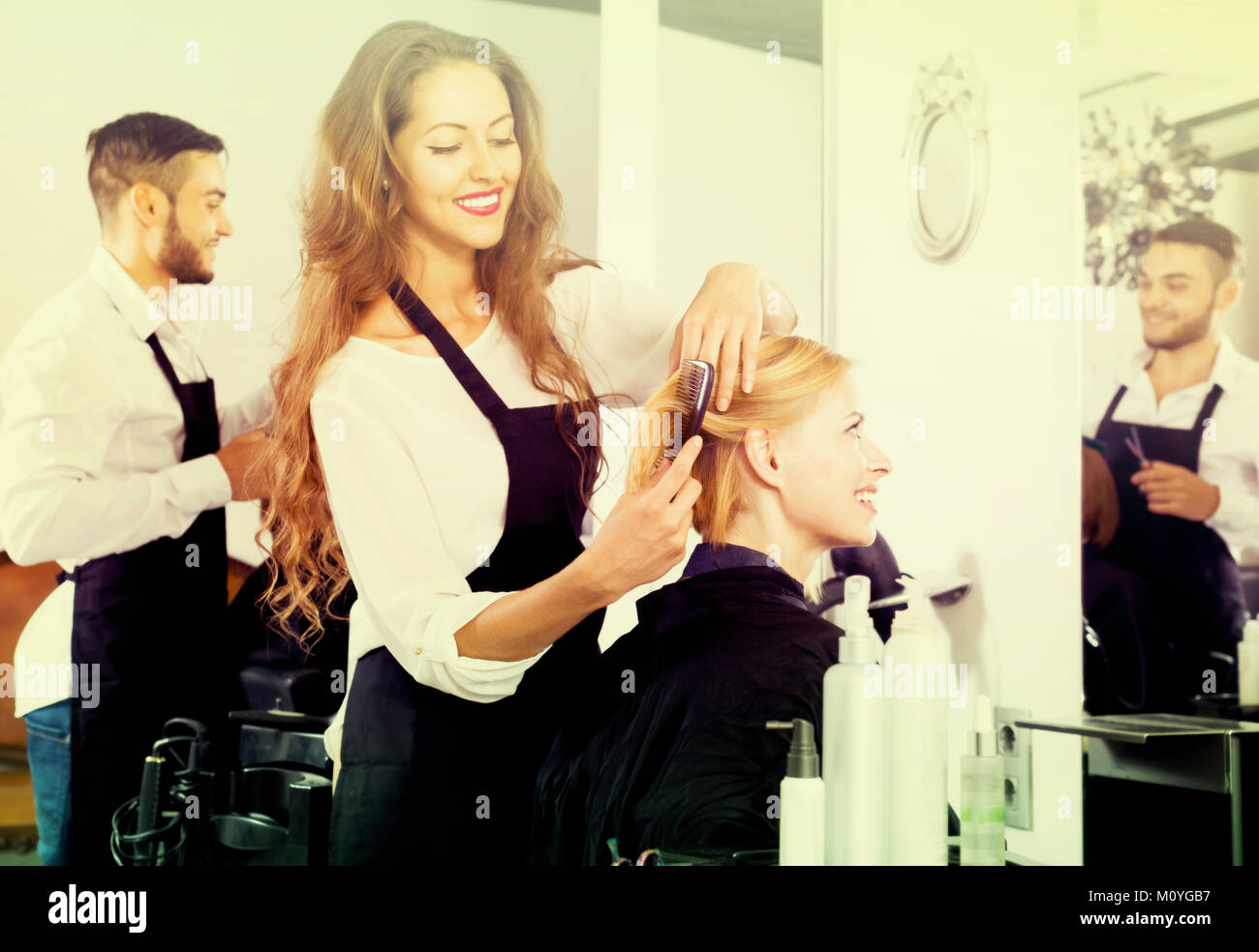 Beautiful hairdresser styling woman's hair with a comb in a salon Stock ...