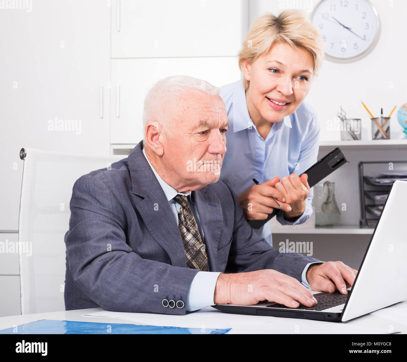 Mature manager and secretary having productive day at work in office ...