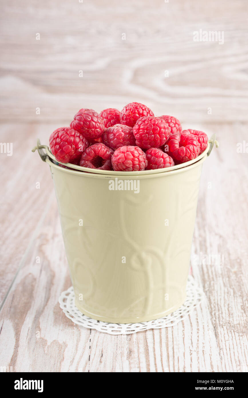 Bucket of fresh tasty raspberries on wooden table Stock Photo - Alamy