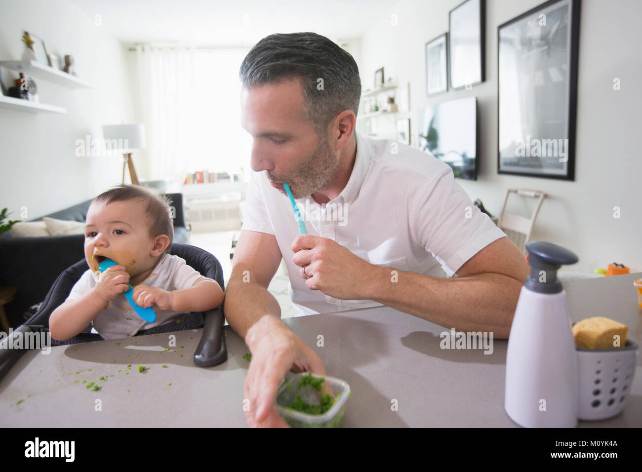 Father watching baby son eating Stock Photo - Alamy