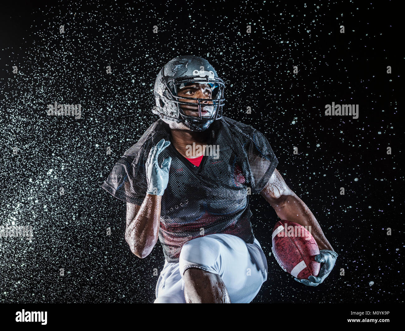Water splashing on black football player running Stock Photo - Alamy