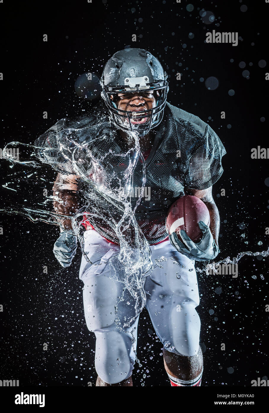 Water splashing on black football player running Stock Photo - Alamy