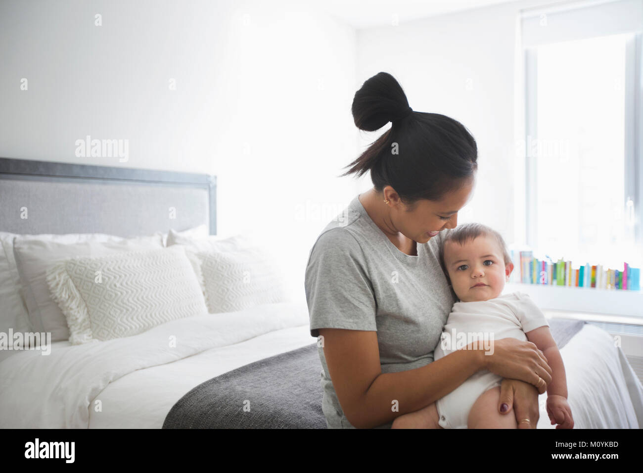 Mother holding baby son in lap on bed Stock Photo - Alamy