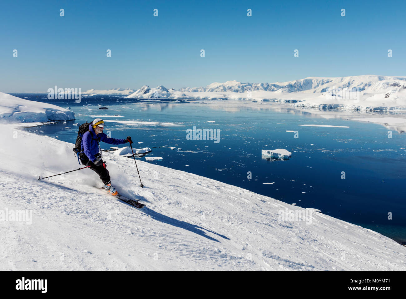 Alpine ski mountaineers skiing downhill; Nansen Island; Antarctica ...