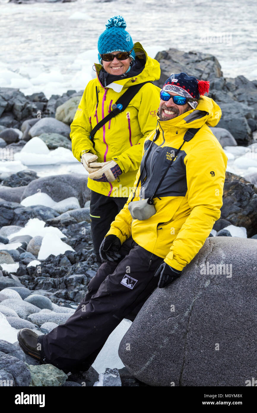 Two professional mountain guides chat on rocky beach; Half Moon Island ...