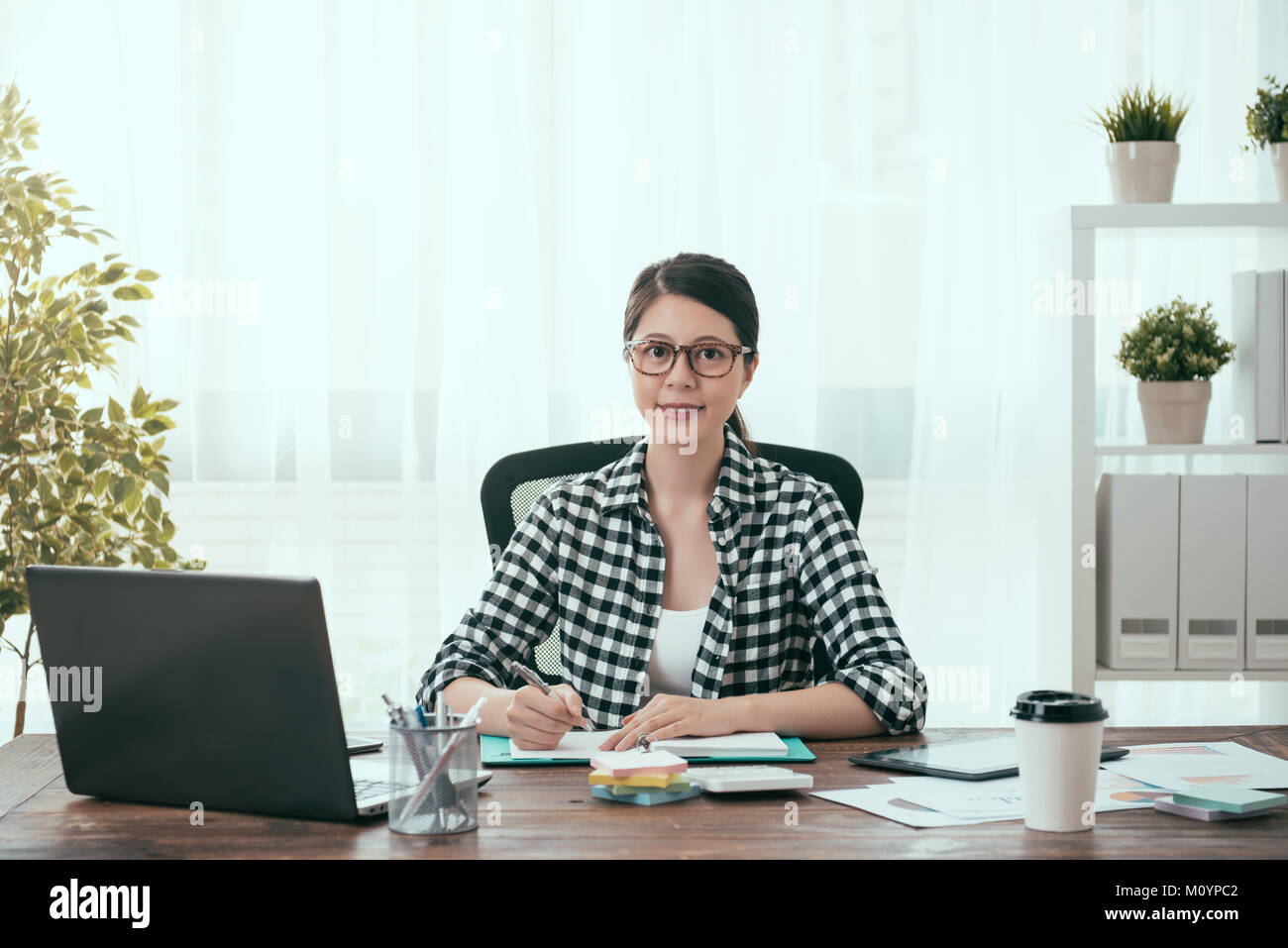 pretty confident female business worker working at home and sitting on ...