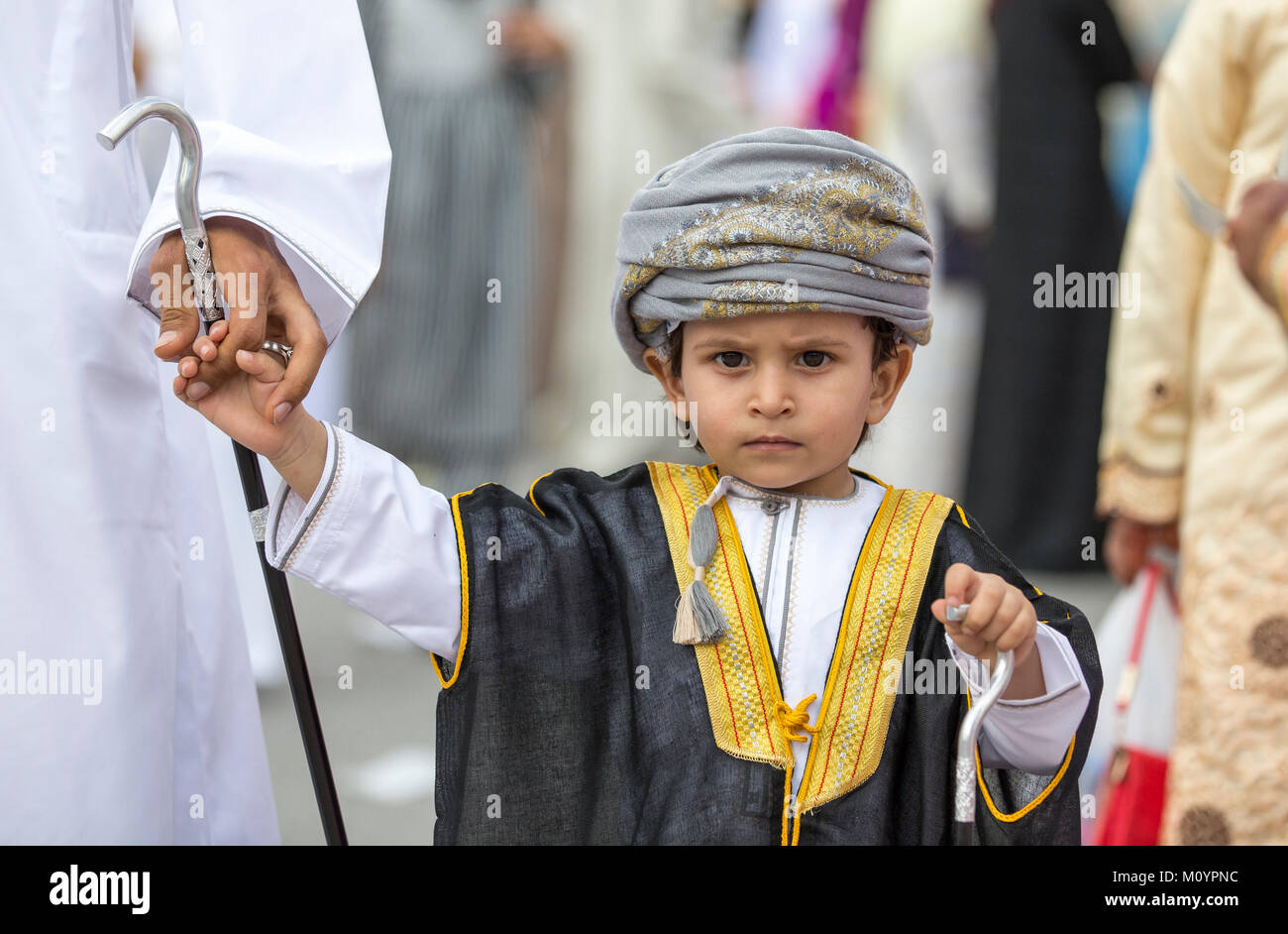 Nizwa, Oman - June 26th 2017: little boy in traditional outfit, holding ...