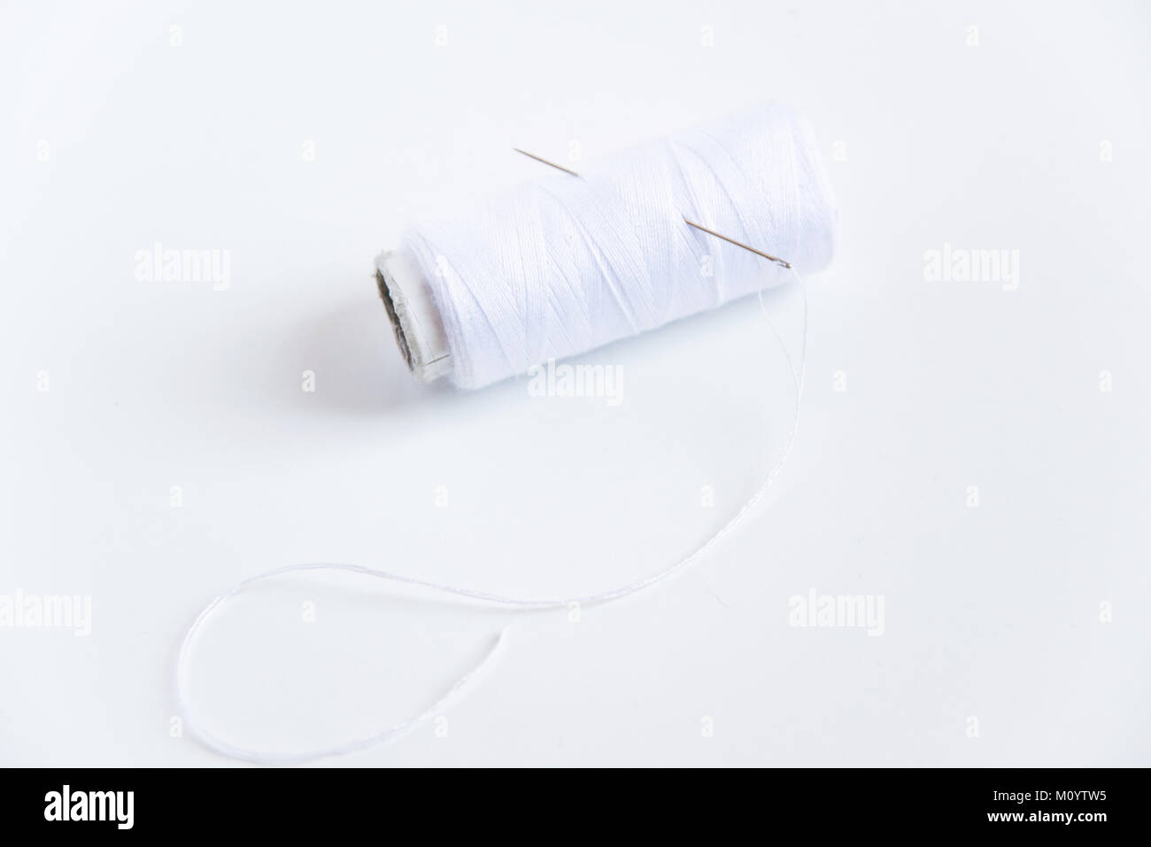White thread and sewing needle on white background with space for text ...