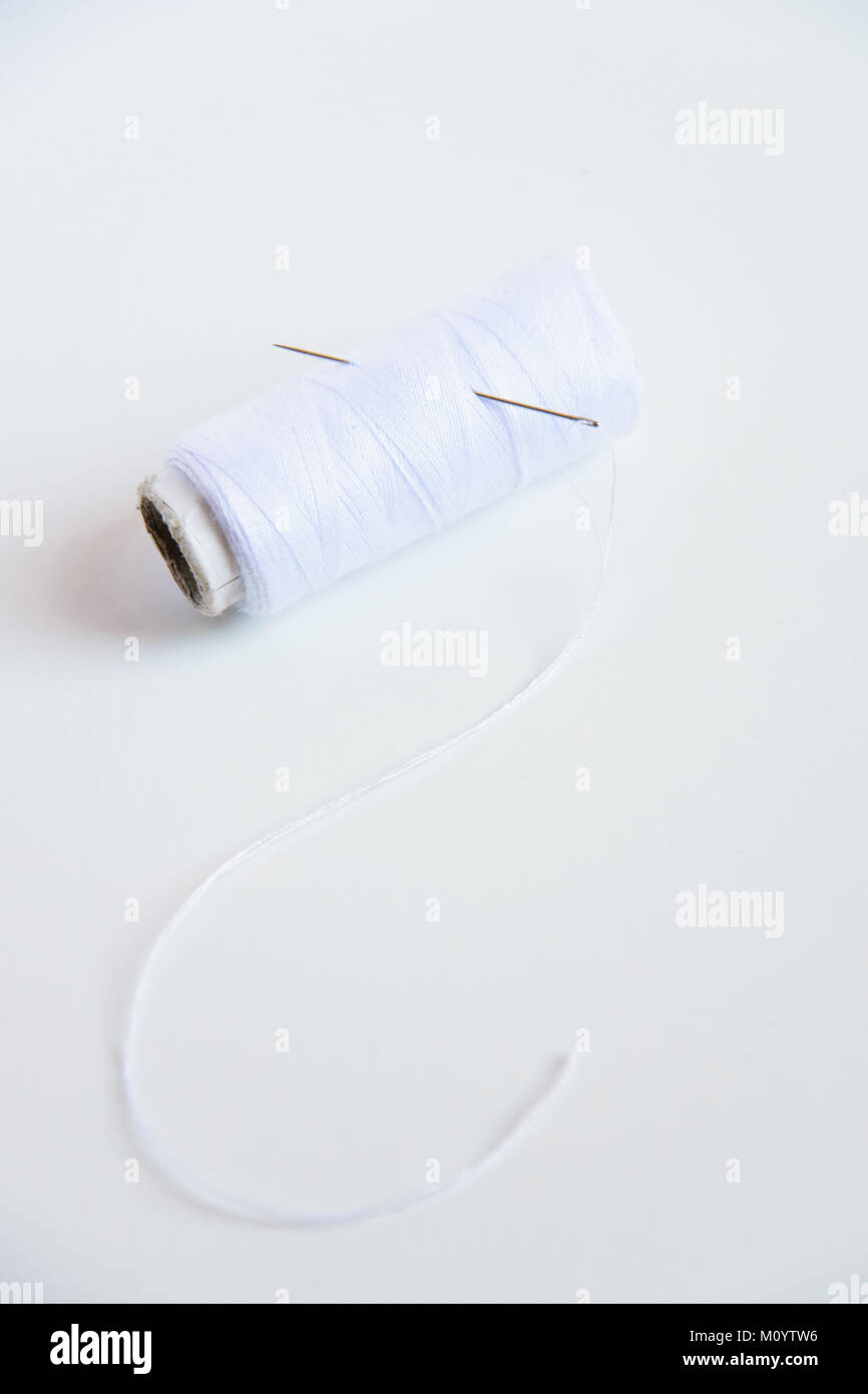 White thread and sewing needle on white background with space for text ...
