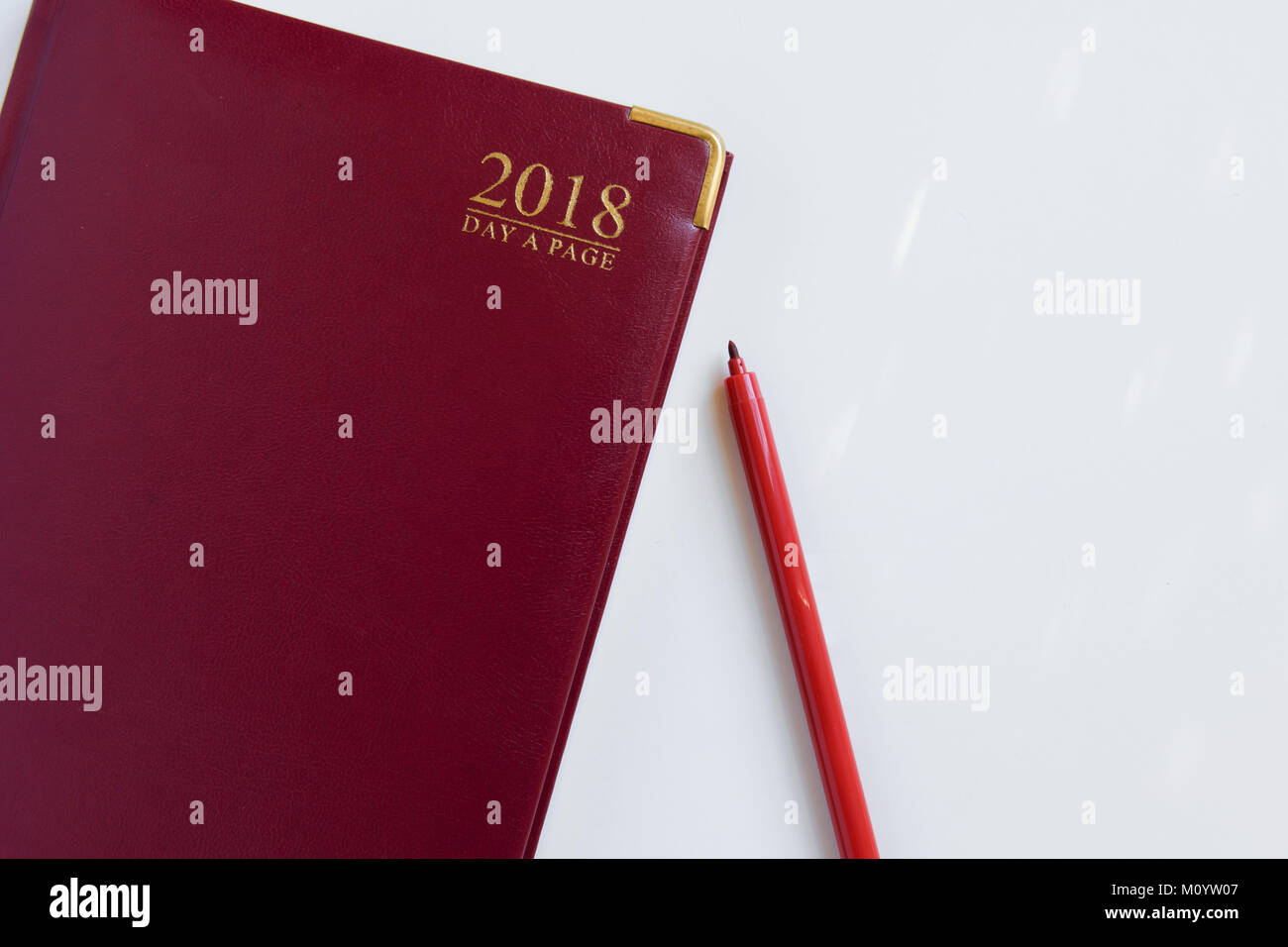 Top view of red diary for 2018 with pen on white background and space ...