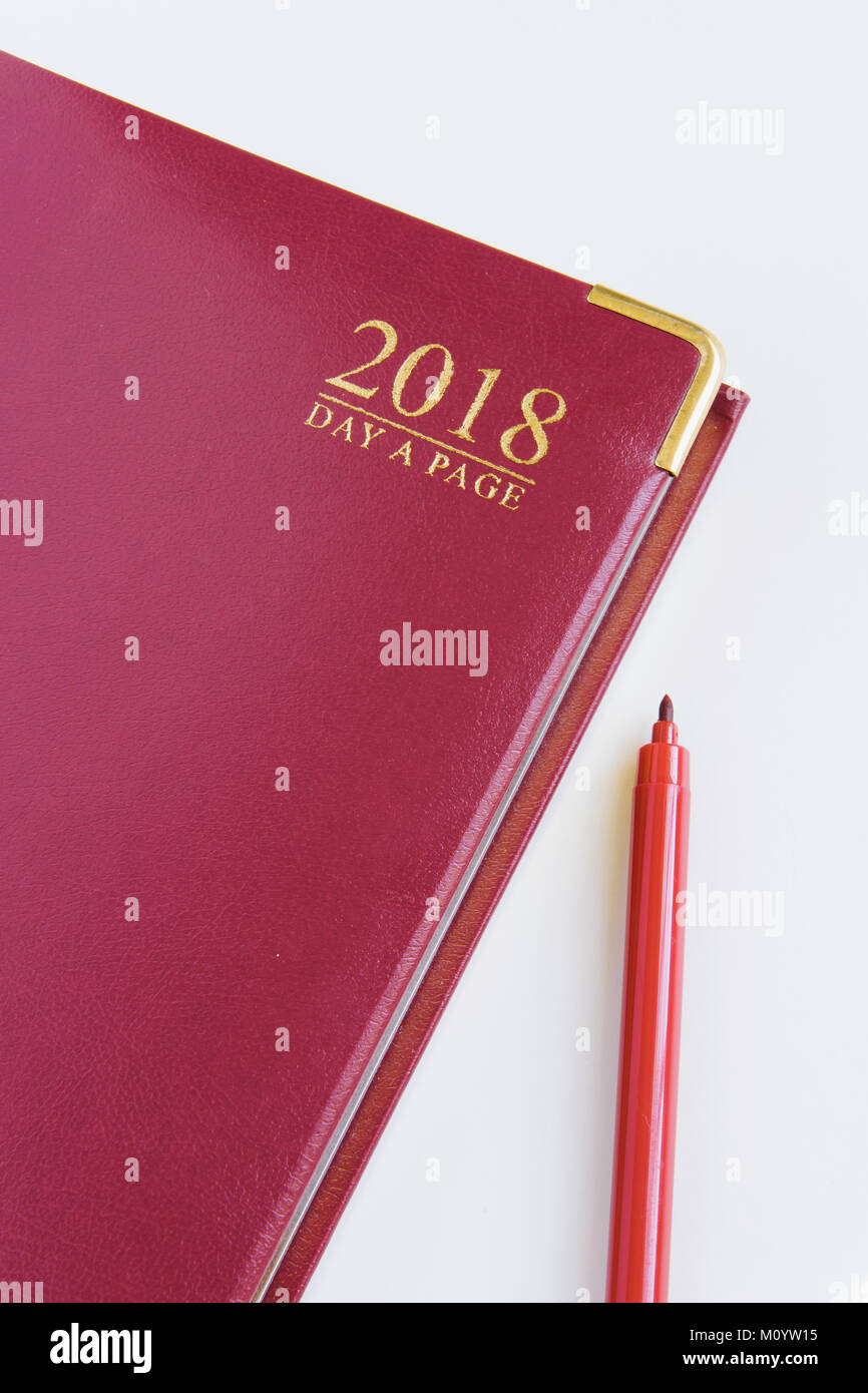 Top view of red diary for 2018 with pen on white background and space ...
