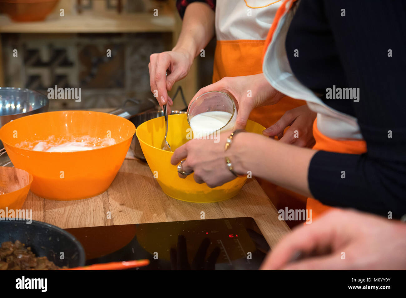 Close up women's hands mixing ingredients for dough in plastic bowls at ...