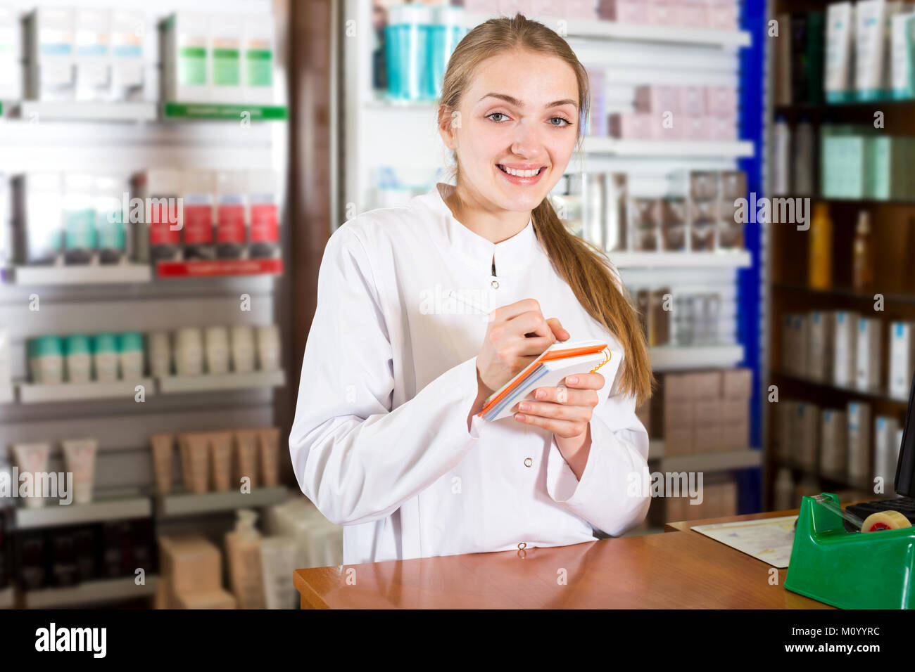 Portrait of positive young female pharmacist working in modern farmacy ...