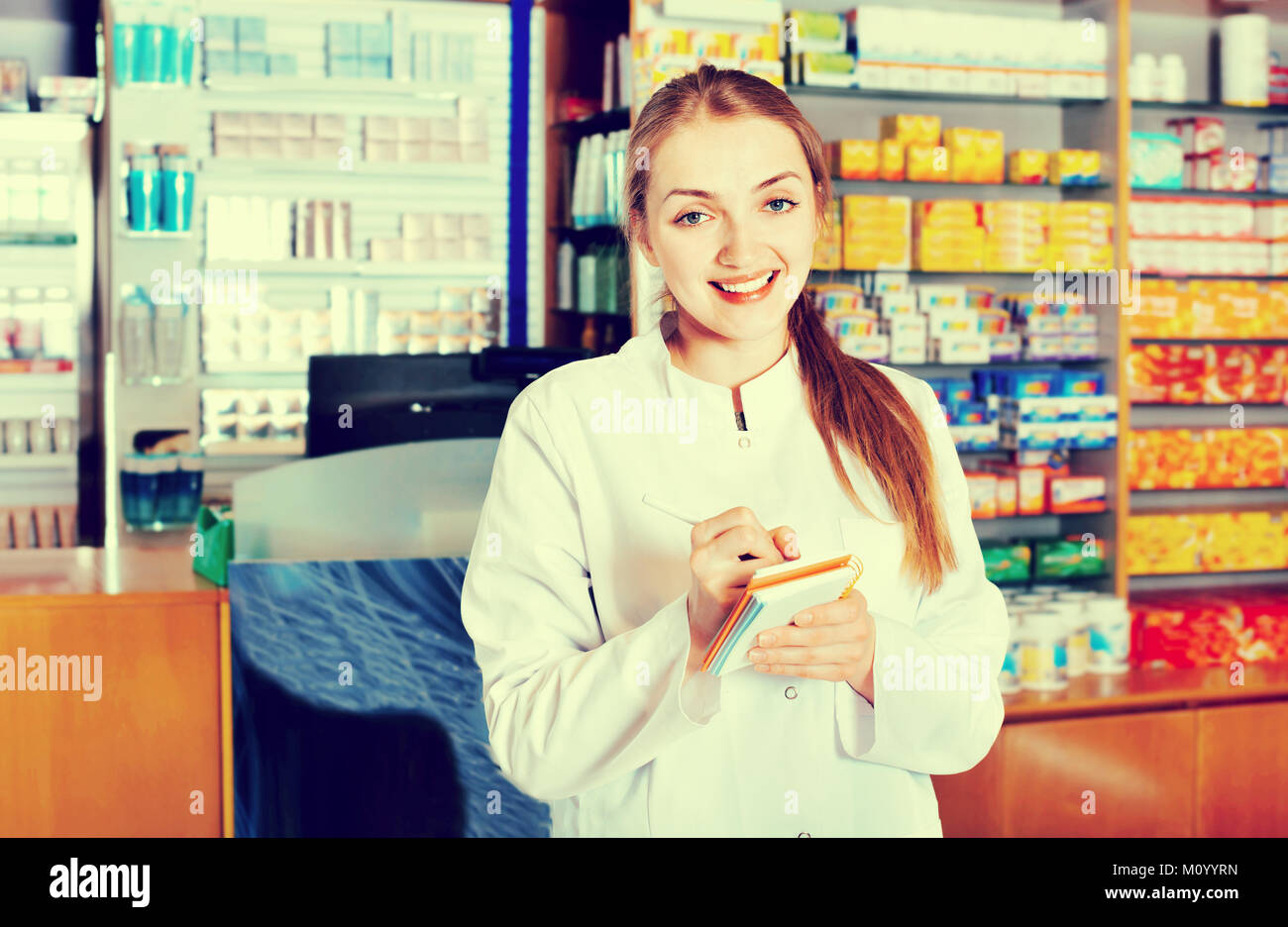 Smiling pleasant young female pharmacist posing in drugstore Stock ...