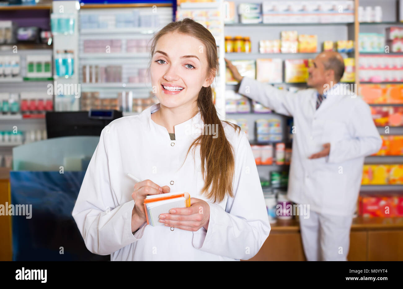Pharmacist and male pharmacy assistant helping in drugstore Stock Photo ...