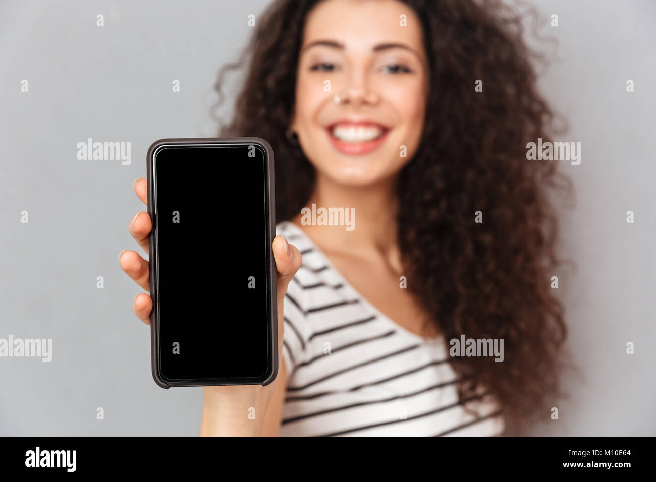 Attractive adult girl with ring in nose demonstrating her mobile phone ...