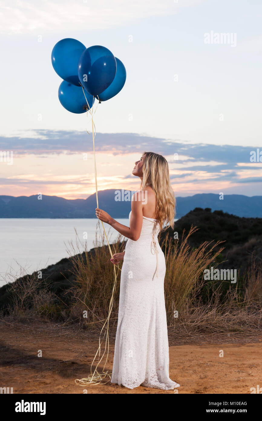portrait of a beautiful bride with balloons enjoy the sunset in the ...