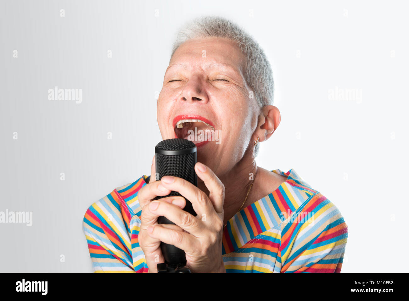 Senior old woman singing on a professional microphone Stock Photo - Alamy