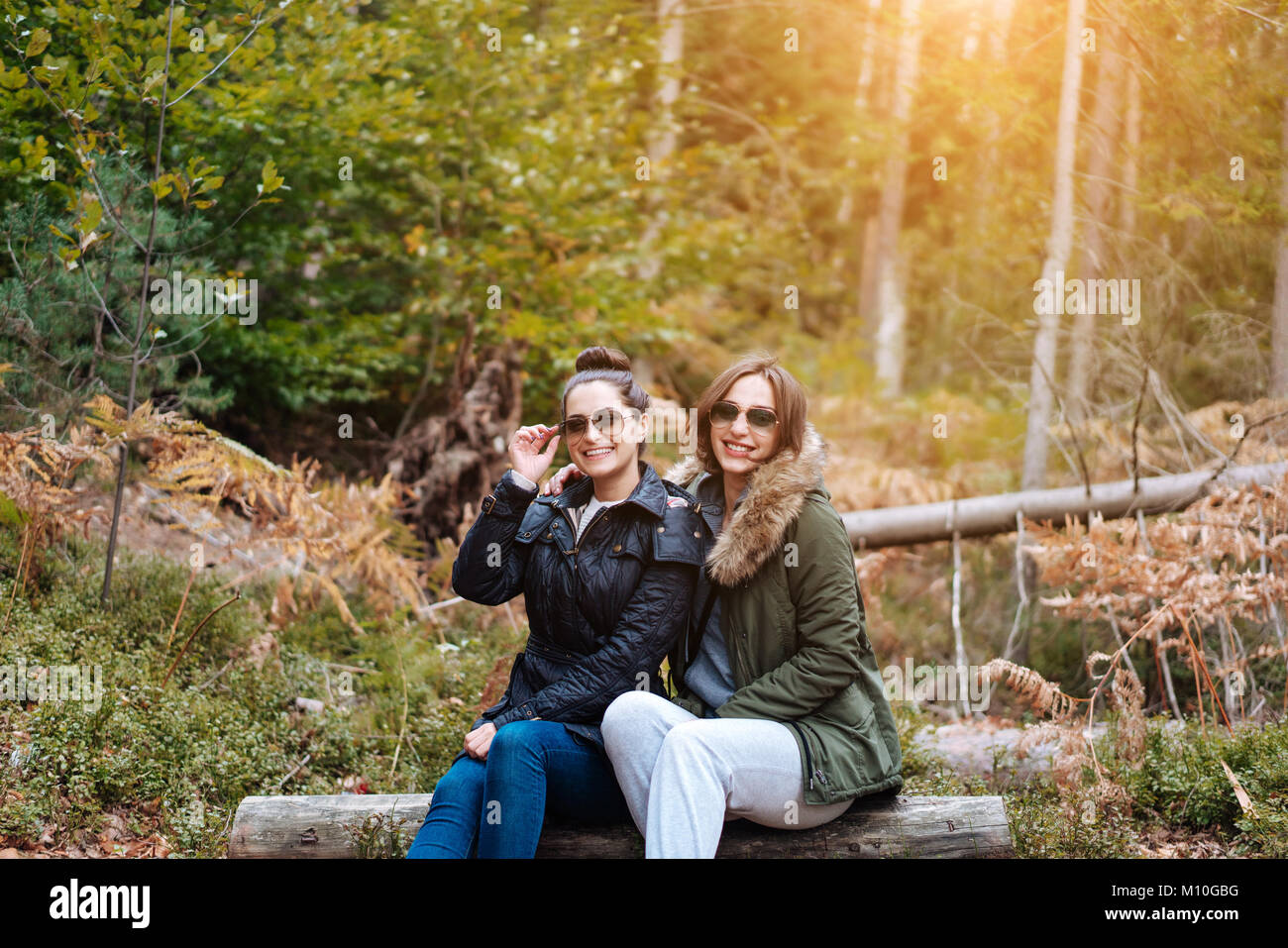 two beautiful girls sat down in the forest Stock Photo - Alamy