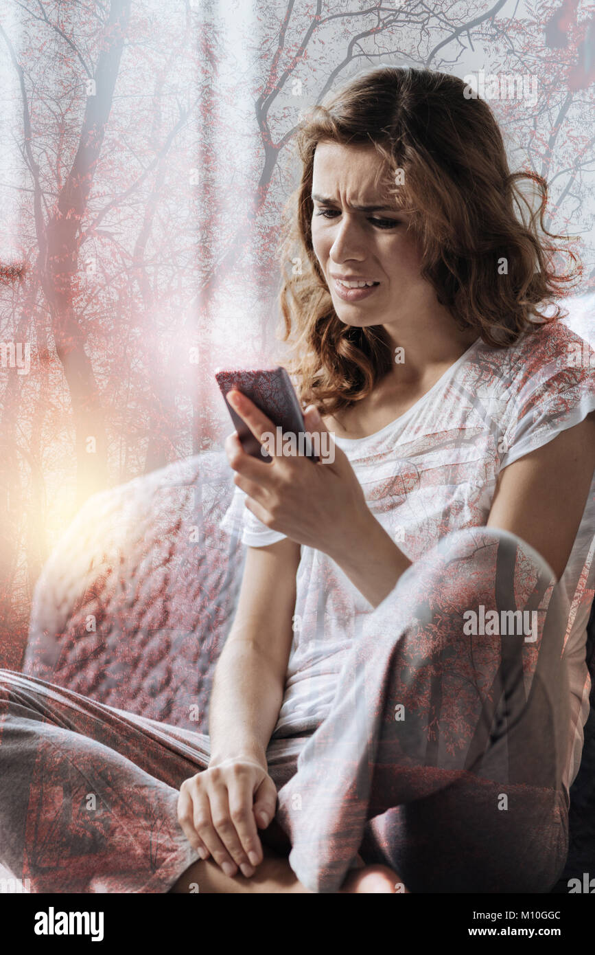 Cheerless woman holding her smart phone Stock Photo - Alamy