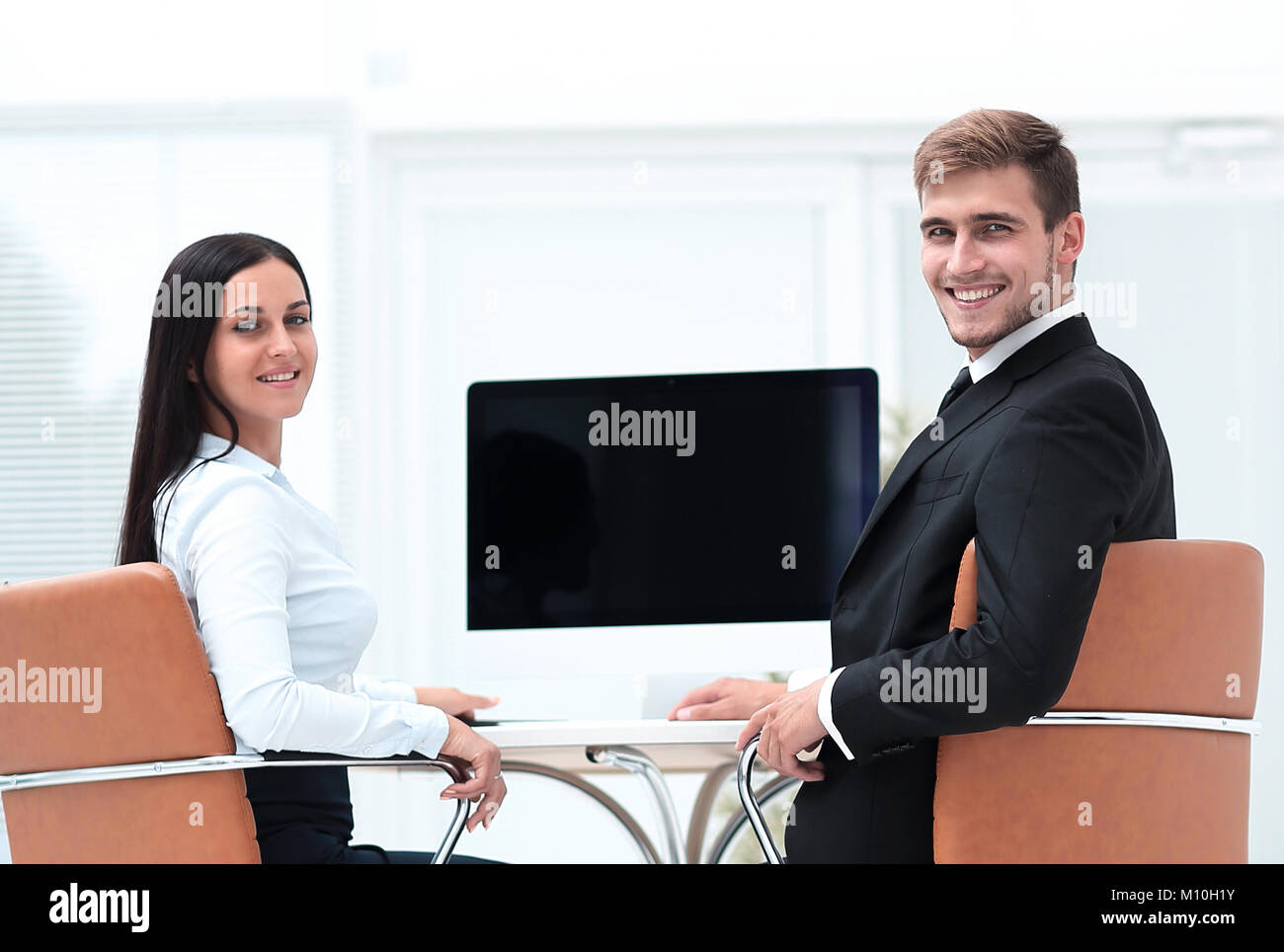 two successful employee sitting behind a Desk Stock Photo - Alamy