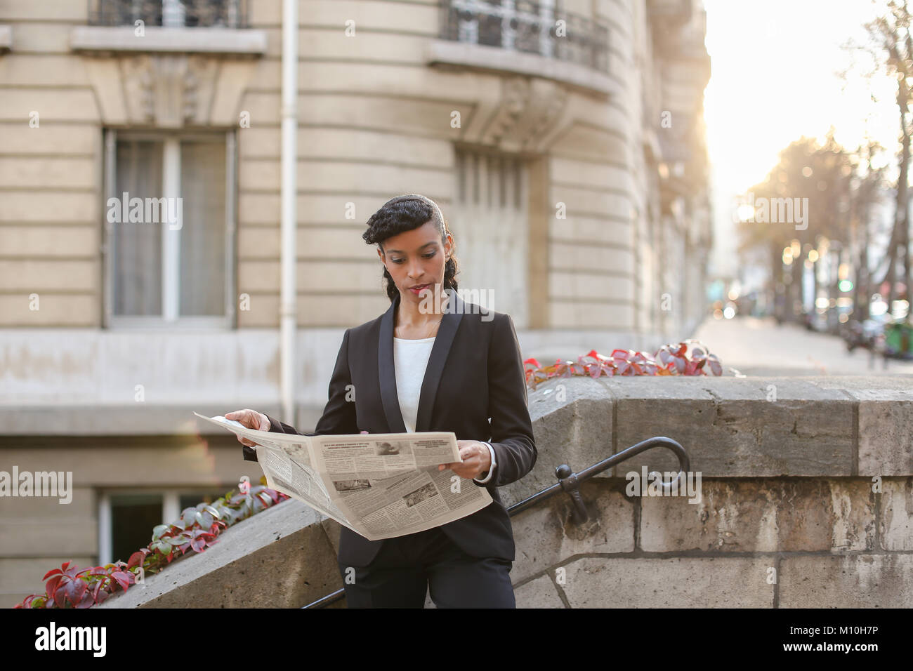 Half Nigerian reporter looking at cam with newspaper on balcony Stock ...