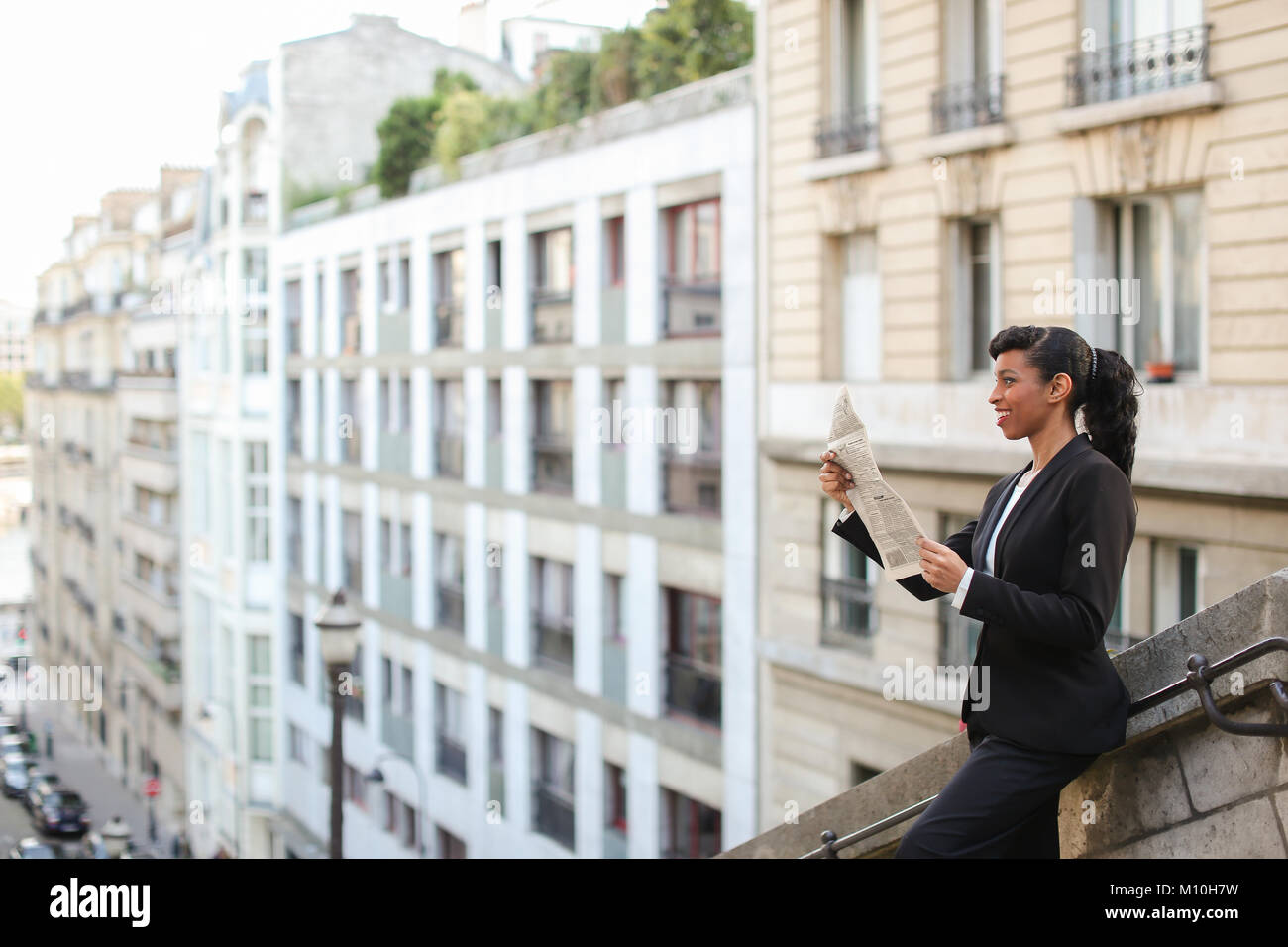 Half Nigerian reporter looking at cam with newspaper on balcony Stock ...