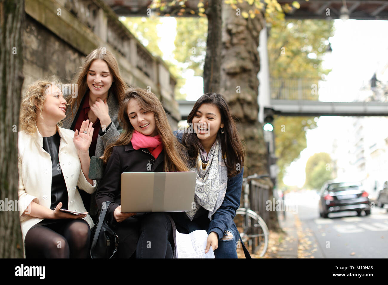 Female students sitting on bench and learning with laptop and pa Stock ...