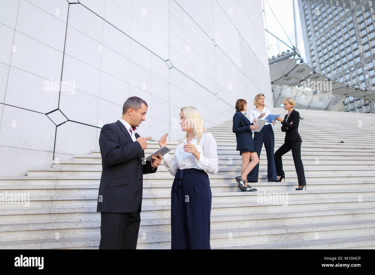 Boss keeping tablet and speaking with blonde secretary on stairs with ...