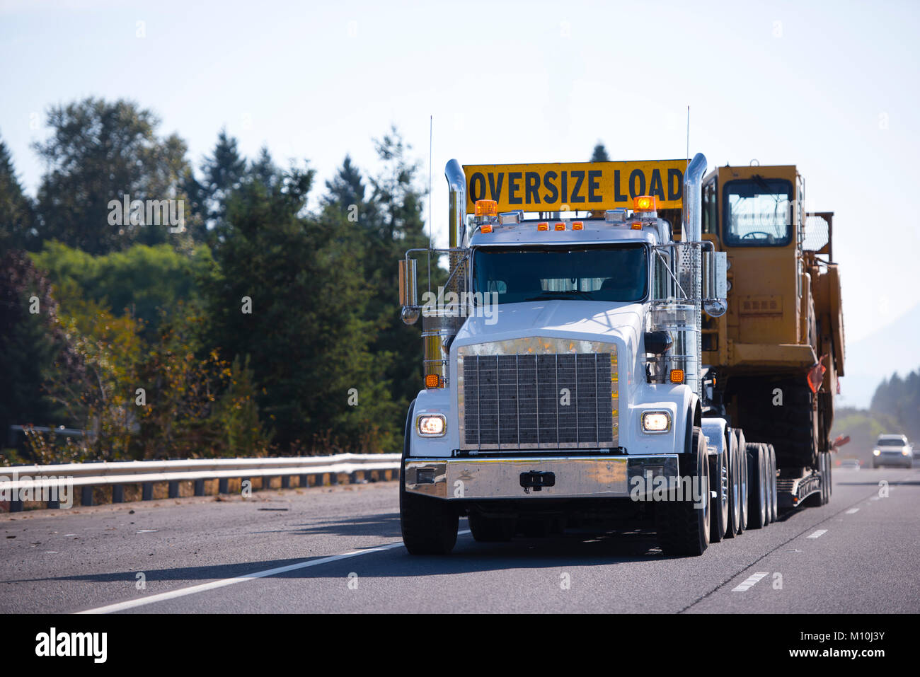 White powerful big rig semi truck with oversize load sign and step down ...