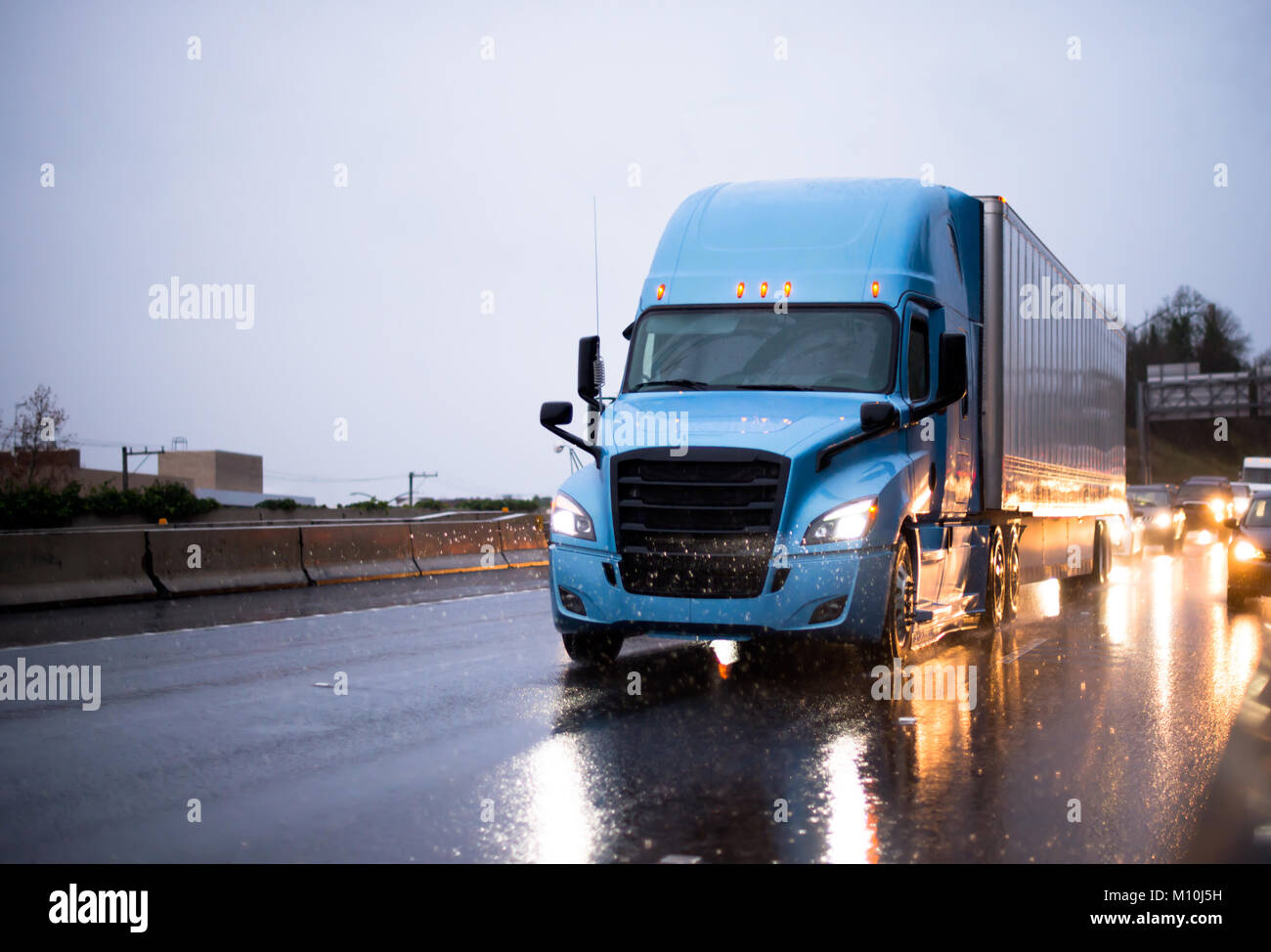 Modern big rig blue semi truck with covered semi trailer driving on ...