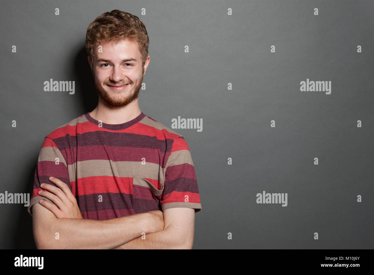 Portrait of a handsome young man smiling against grey background Stock ...