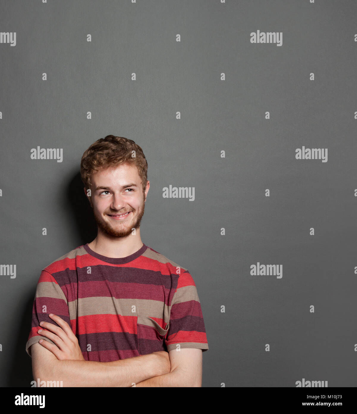 Portrait of a handsome young man thinking and smiling against grey ...
