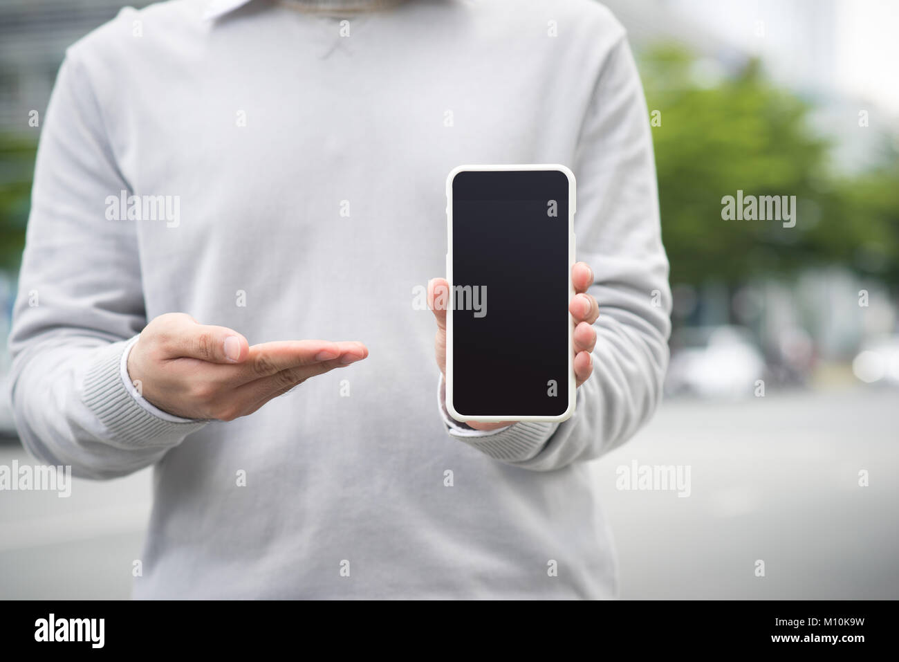 Businessman holding and showing screen of cellphone Stock Photo - Alamy