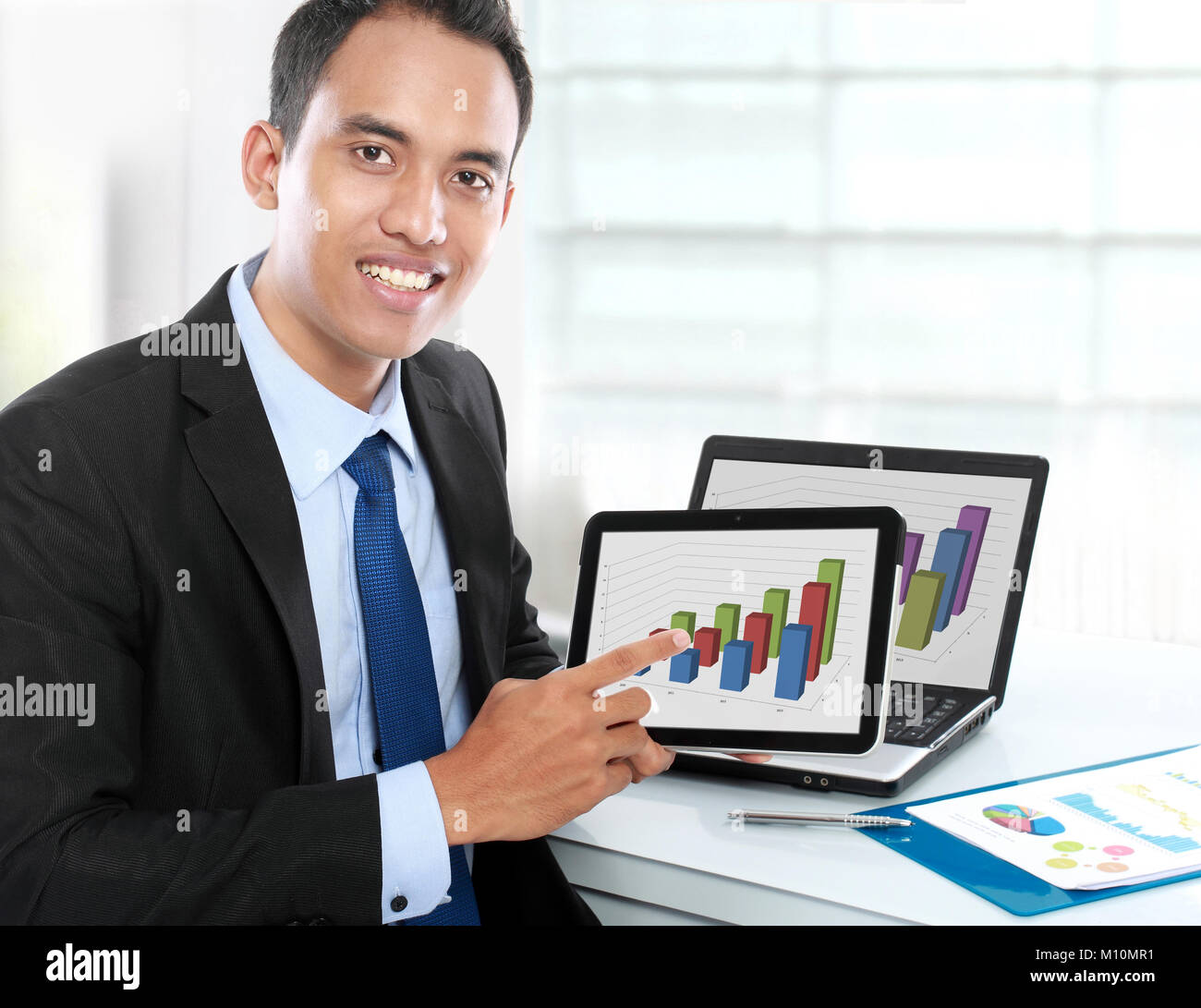Business man showing tablet pc with success growth graph on screen ...