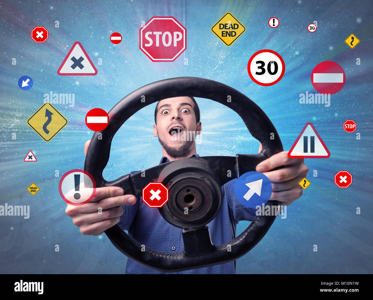 Young man holding black steering wheel with road signs surrounding him ...